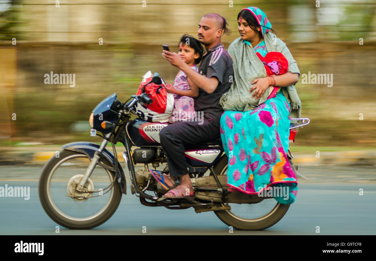A Panning image of a family of three on a motorcycle, all without ...
