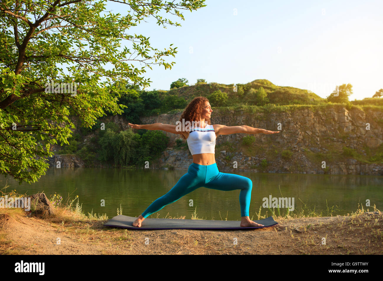 Young woman is practicing yoga near river Stock Photo - Alamy