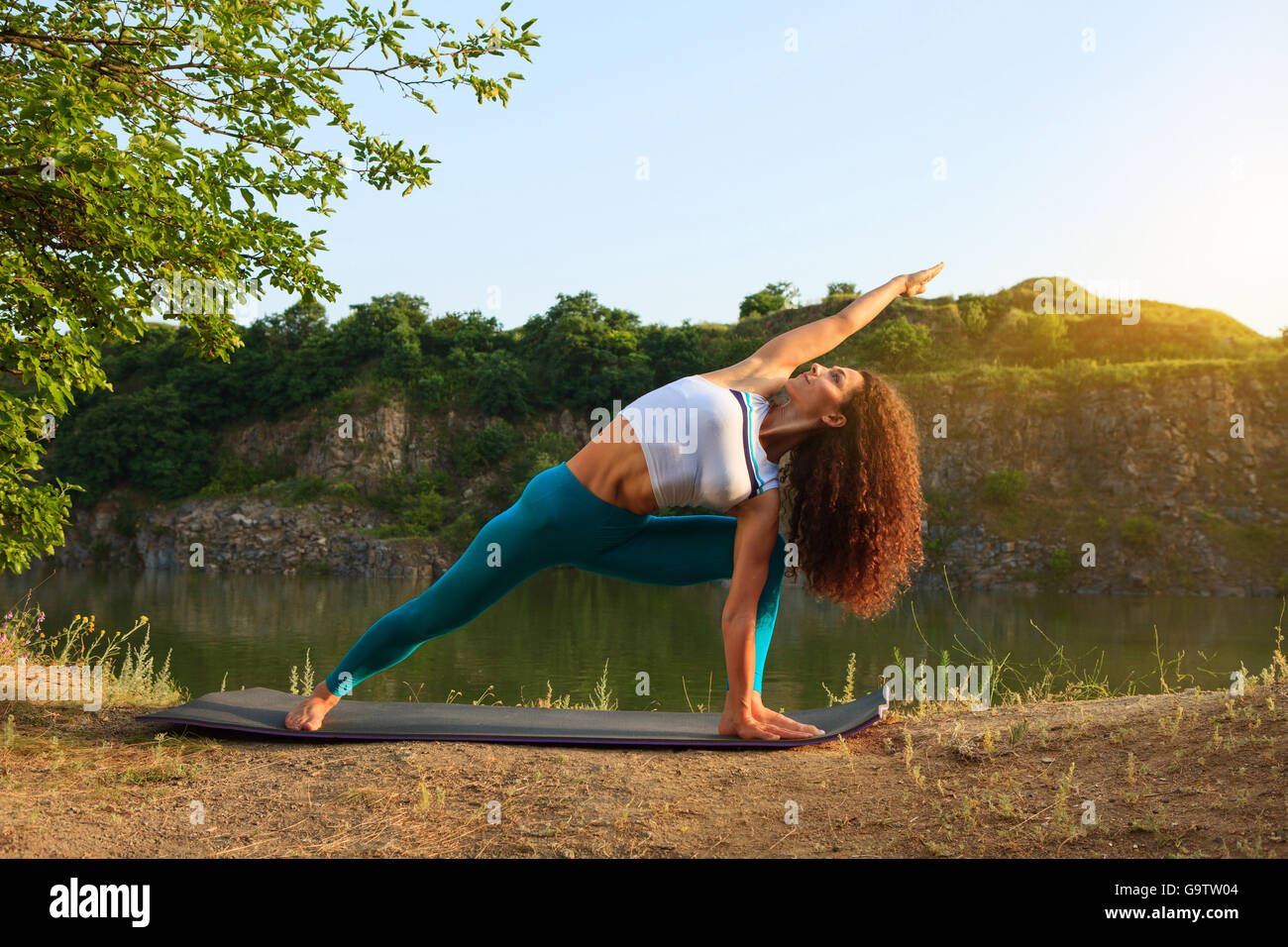 Young woman is practicing yoga near river Stock Photo - Alamy