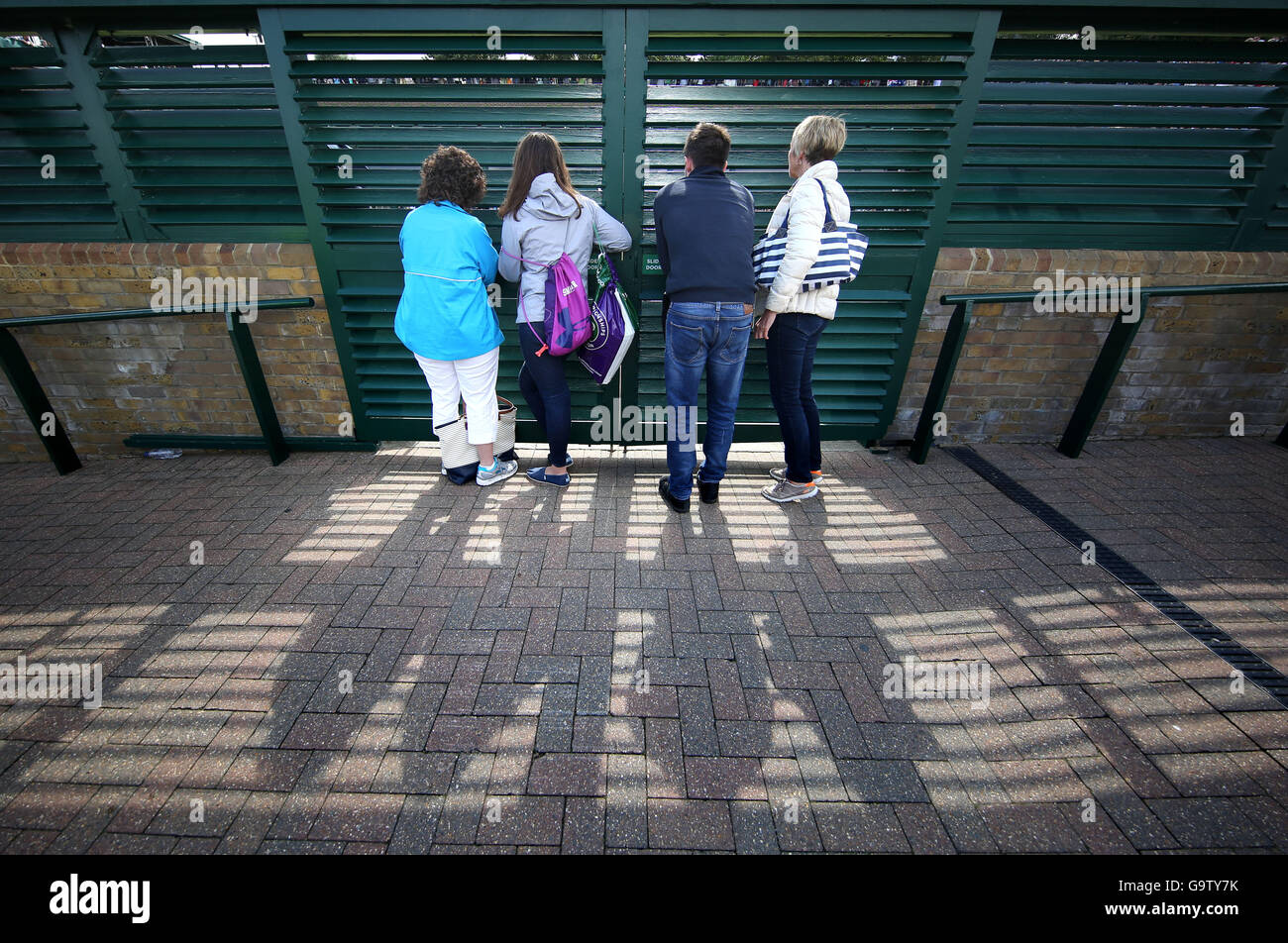 Spectators watch tennis through a gate on court 18 on day five of the ...