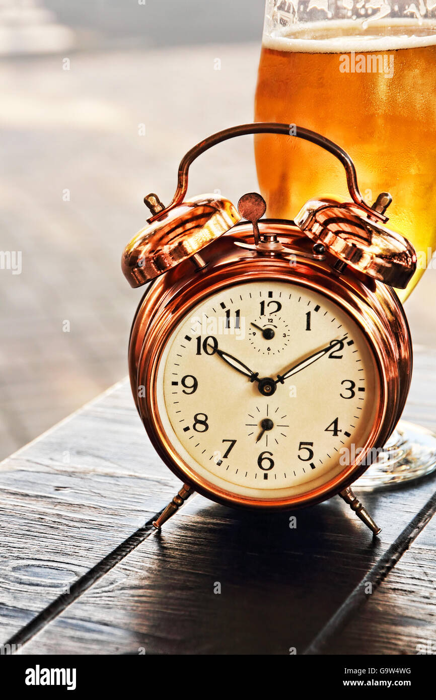 Lunch break-time.Vintage alarm clock and beer glass on table.Toned ...