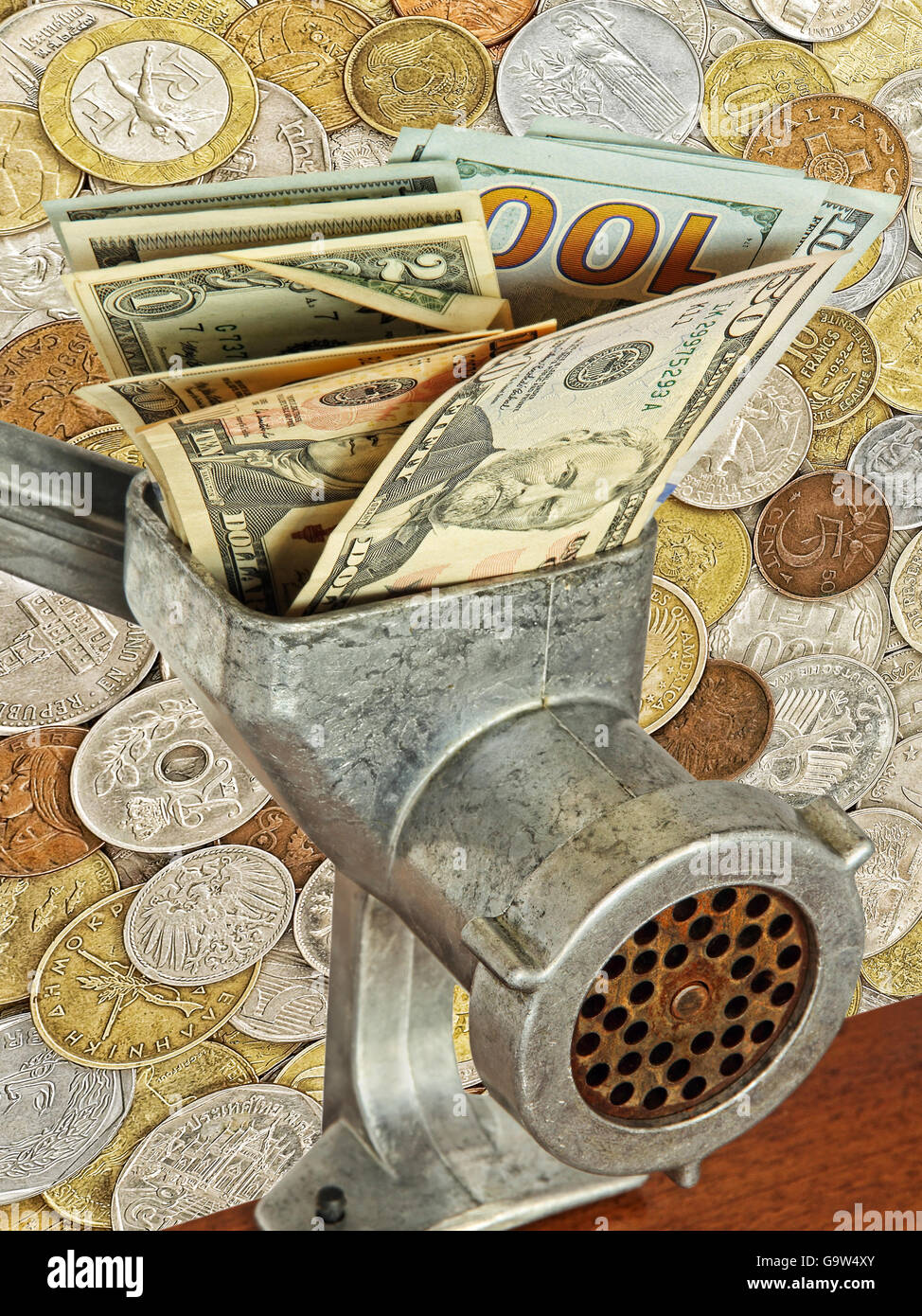 Dollar banknotes in meat grinder on a lot of different coins background ...
