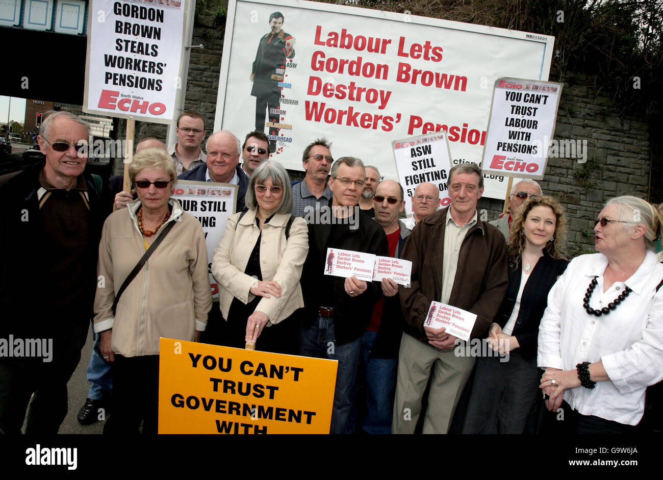 Protesters stand below a poster depicting Chancellor Gordon Brown ...