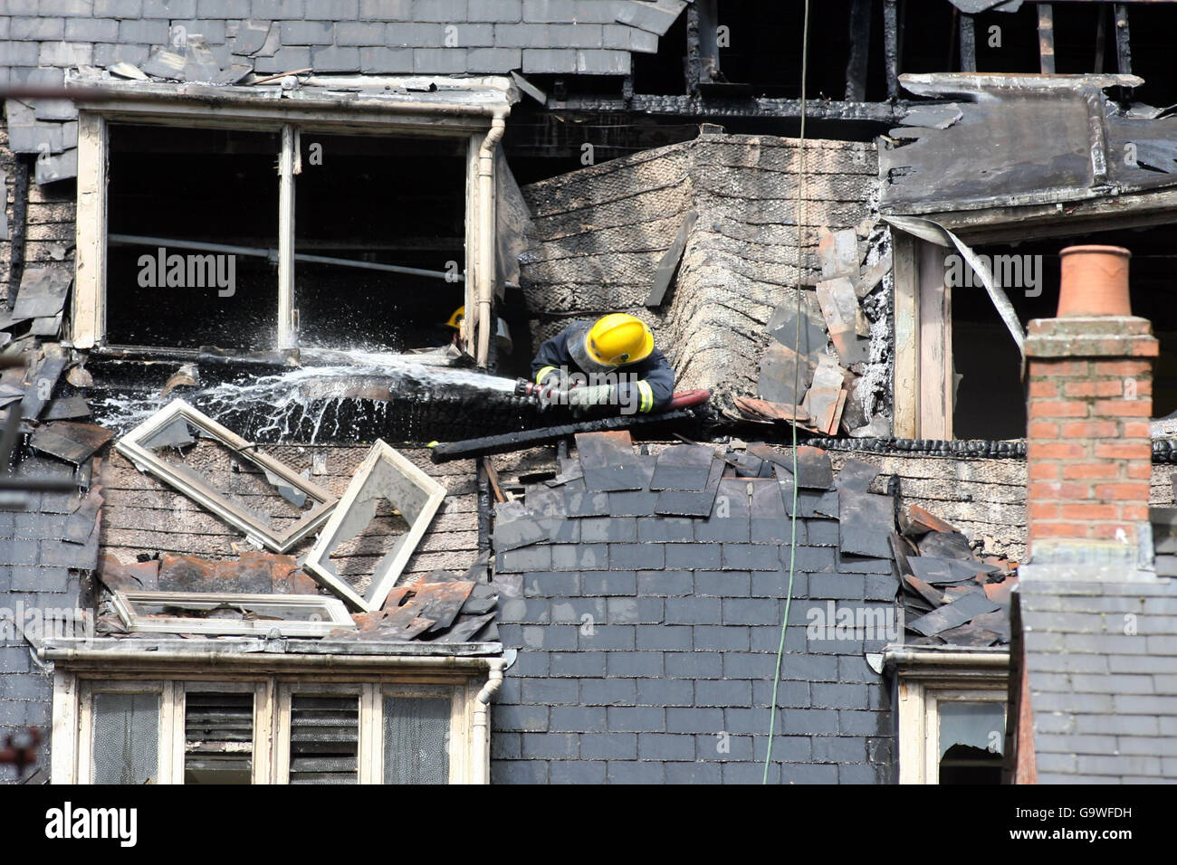A firefighter on the roof of a building whose roof was set on fire ...