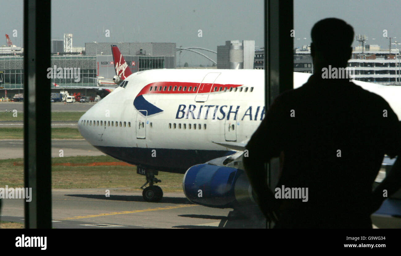 A passenger looks out of a window at Heathrow Airport's Terminal 4 as a ...