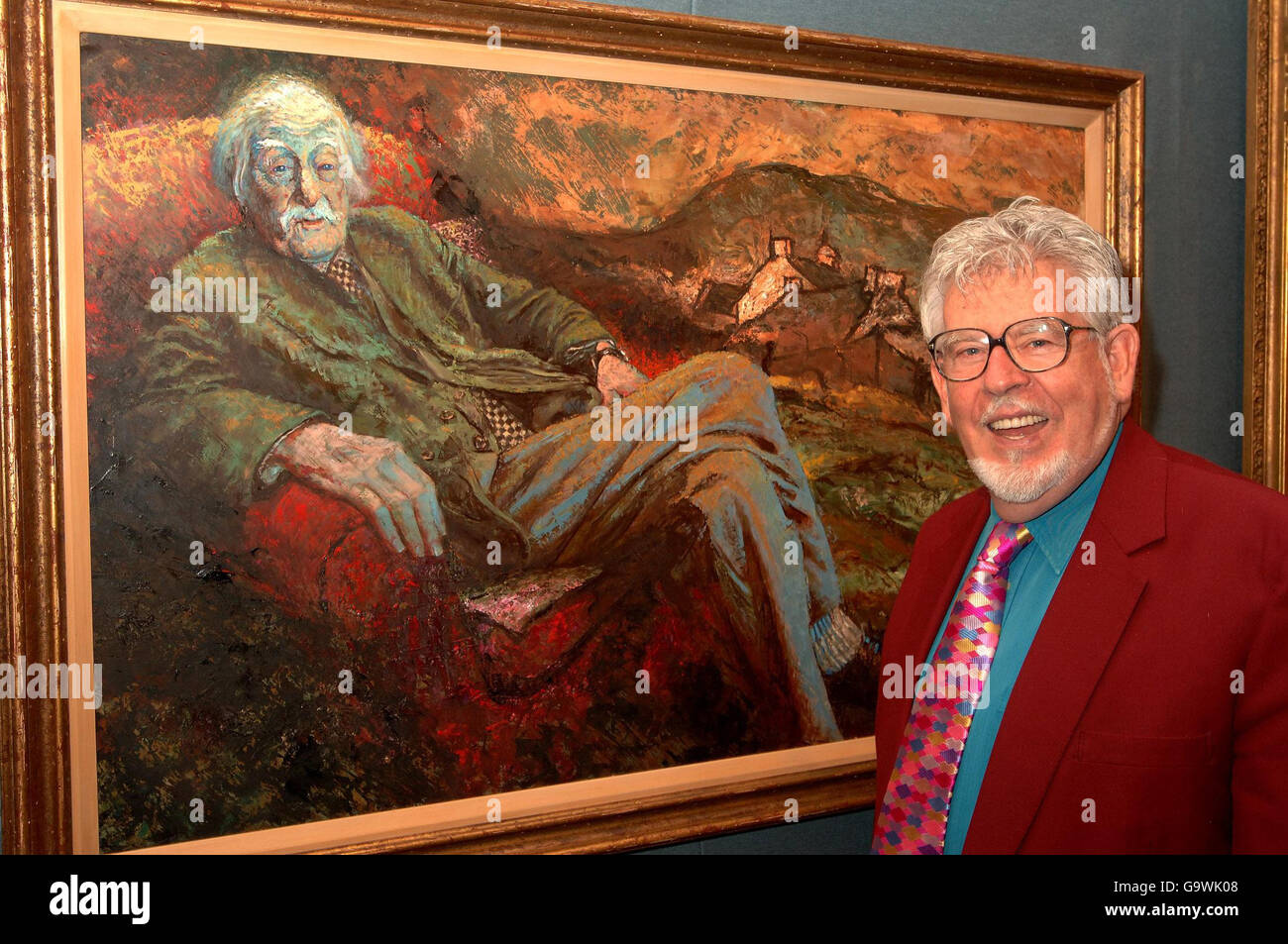 Rolf Harris stands in front of his portrait of Welsh painter Sir Kyffin ...