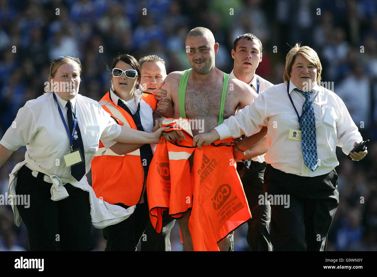A streaker is led away by stewards during the Coca-Cola Football ...