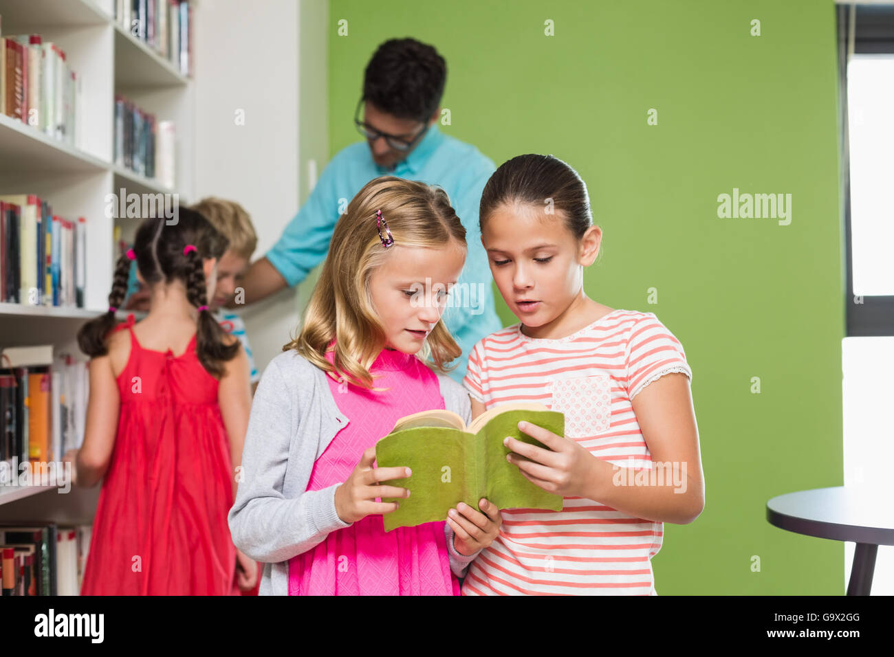 Kids reading book in library Stock Photo - Alamy