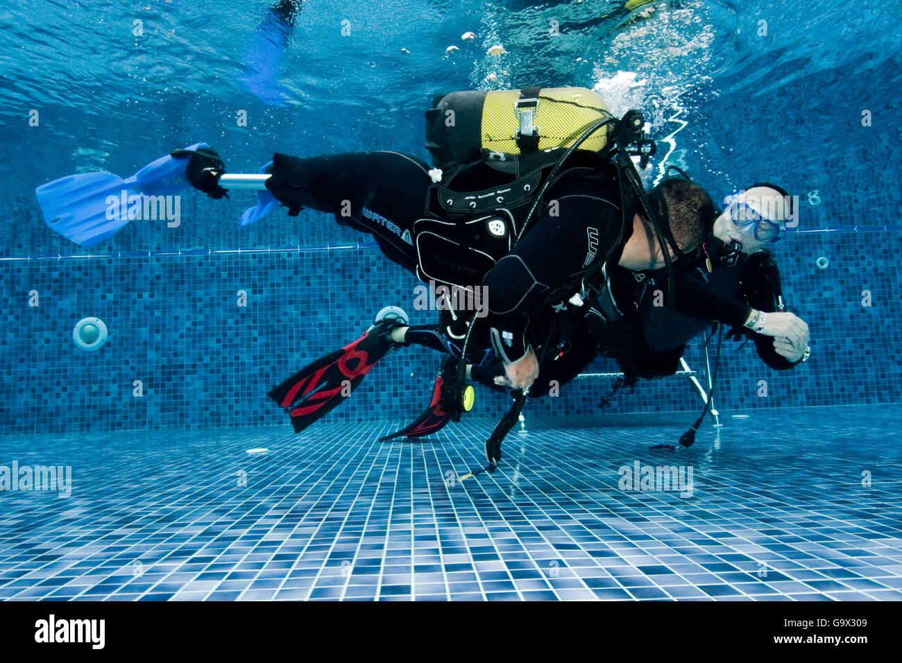 Handicapped diver with leg prothesis dive instructor at swimming pool ...