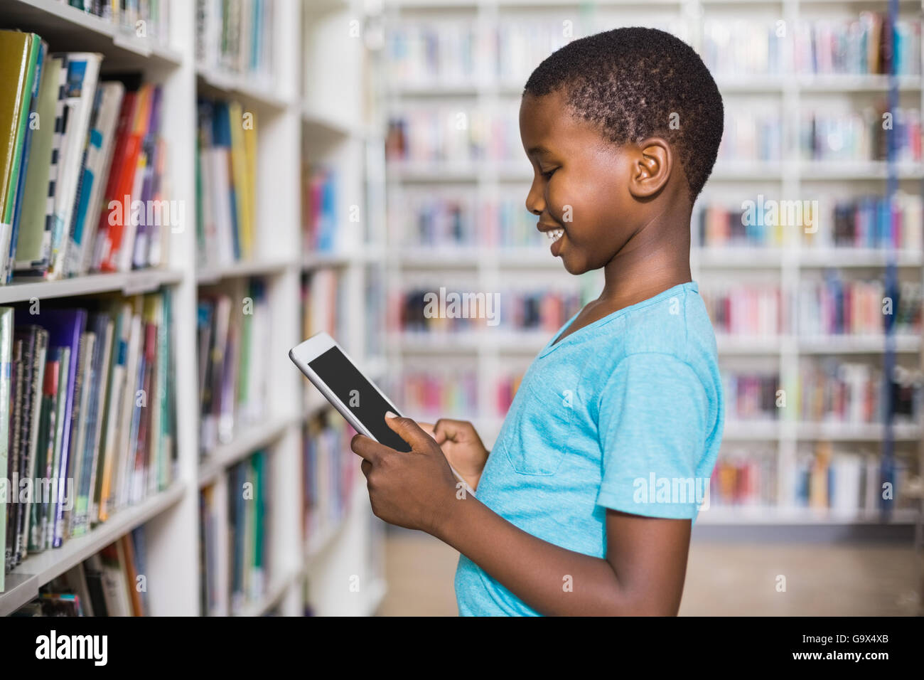 Schoolboy using digital tablet in library Stock Photo - Alamy