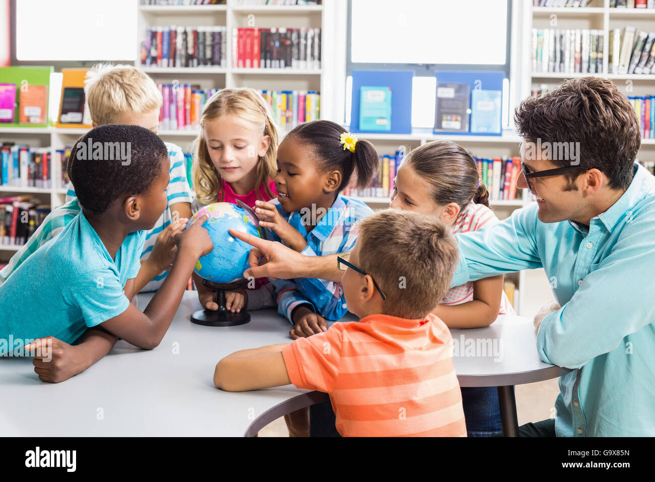 Teacher and kids discussing globe Stock Photo - Alamy