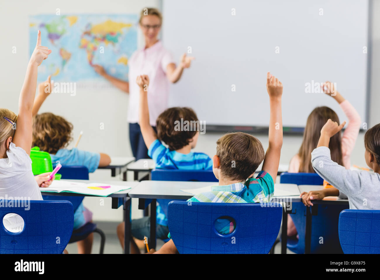 Kids raising hand in classroom Stock Photo - Alamy