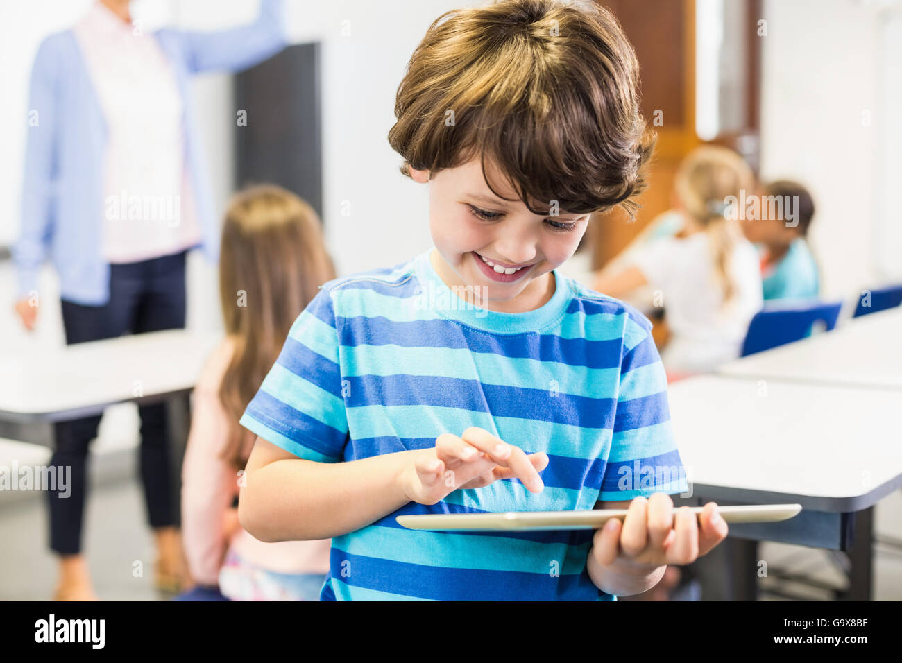 Smiling schoolboy using digital tablet in classroom Stock Photo - Alamy