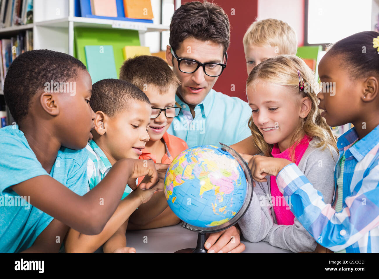Teacher and kids discussing globe Stock Photo - Alamy