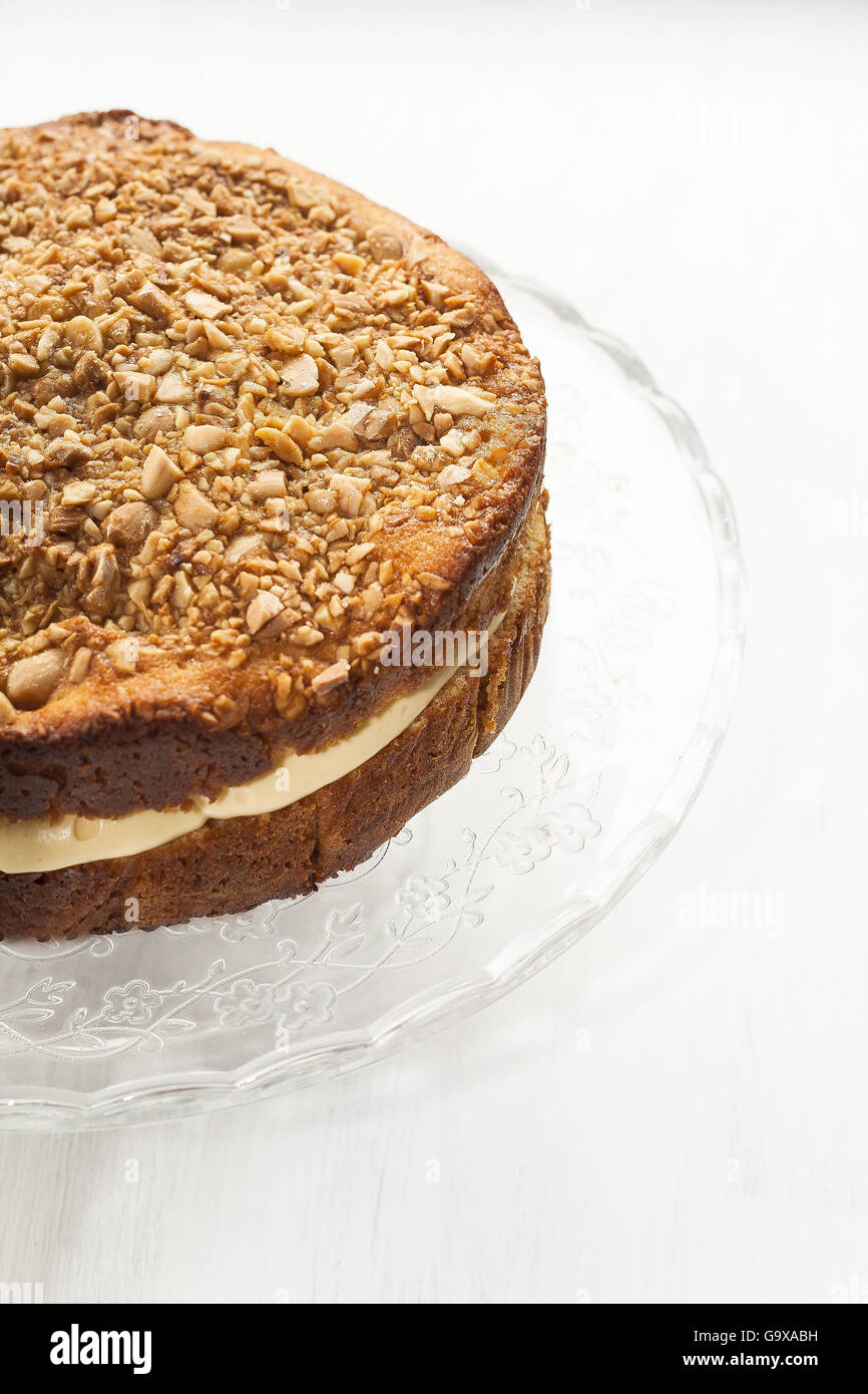 Round a vanilla cake with cream and sprinkled nuts watered honey Stock ...