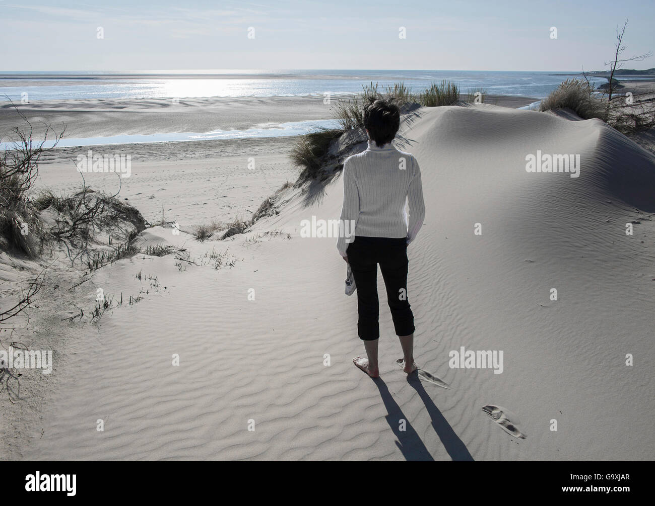 Woman on beach looking out to sea, at mouth of Authie river, Berck ...
