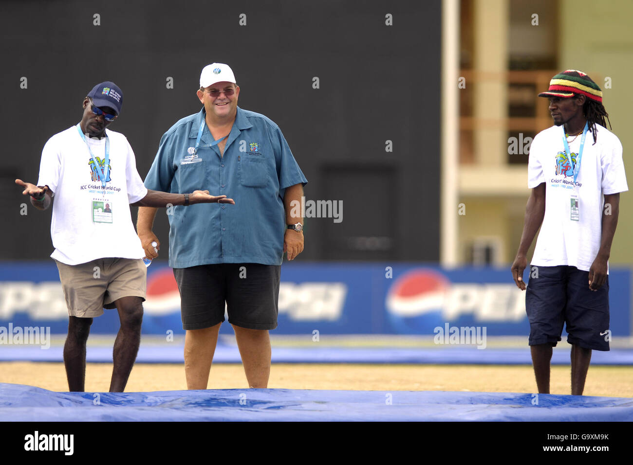 ICC groundsman from Britain, Andy Atkinson (c), instructs his staff ...