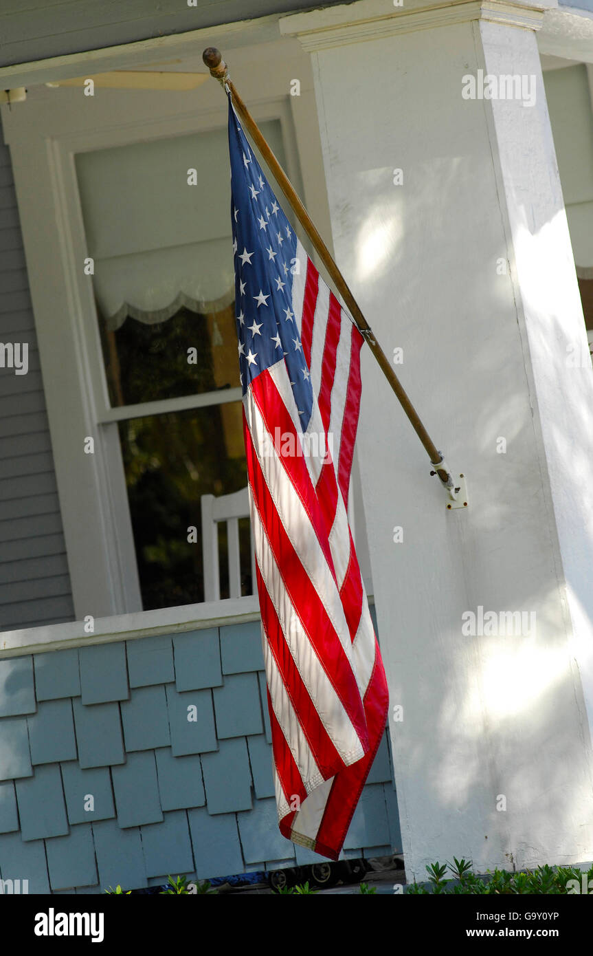 American Flag Stars and Stripes on pillar of house in dappled sunlight ...