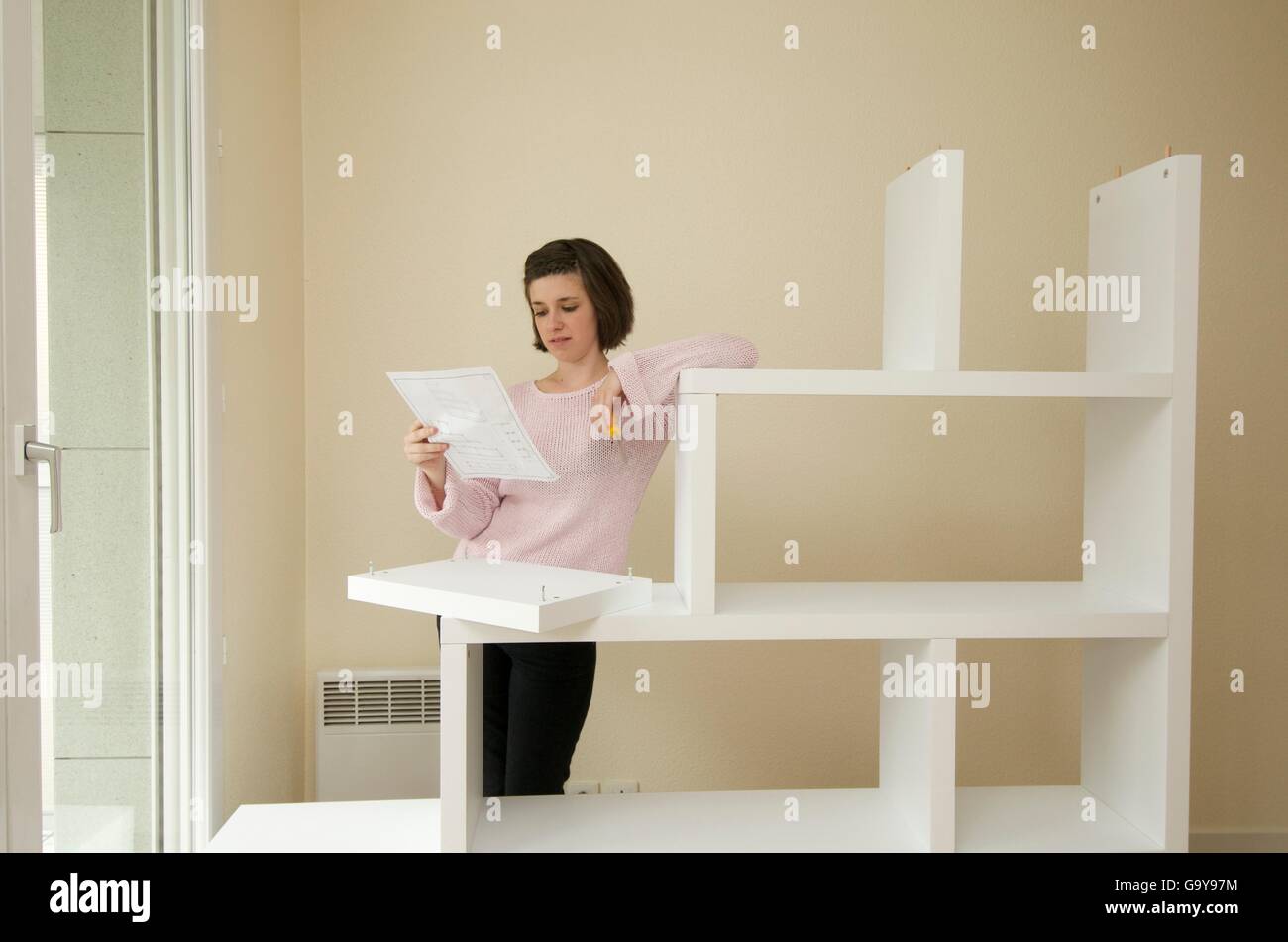 Young woman assembling a shelf Stock Photo - Alamy