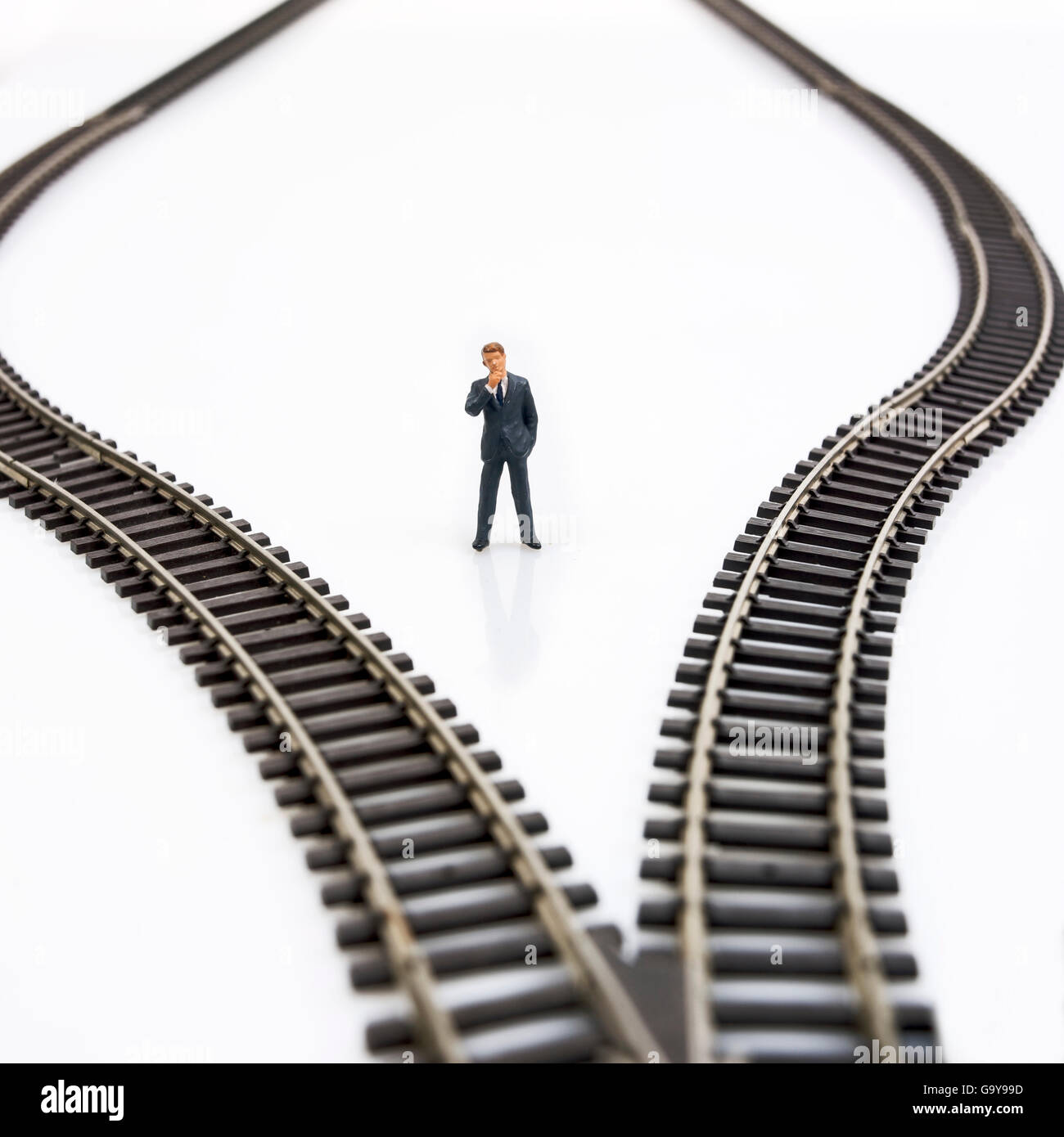 Figurine between two tracks leading into different directions, symbolic ...