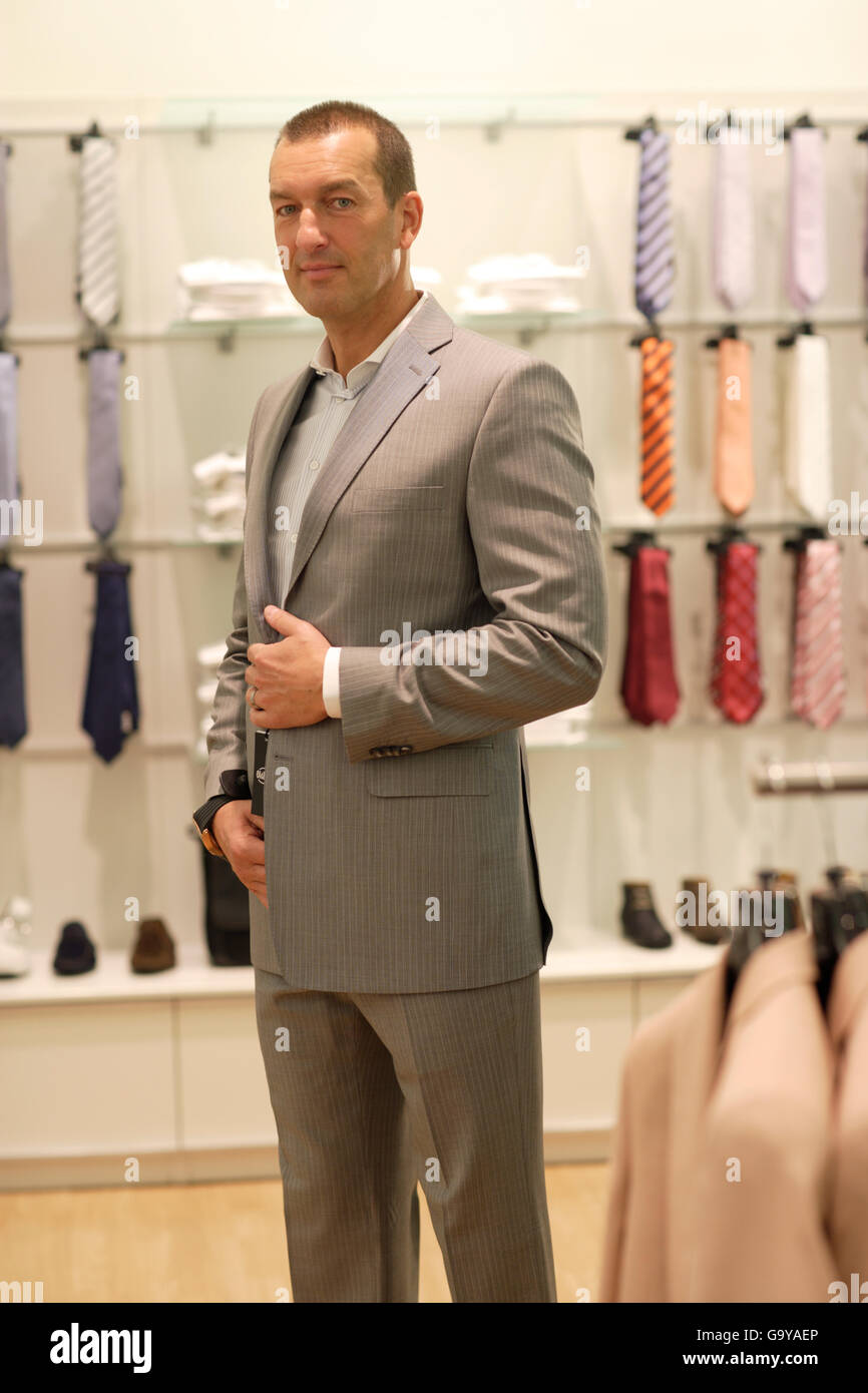 A man selecting clothes in a men's outfitter Stock Photo - Alamy