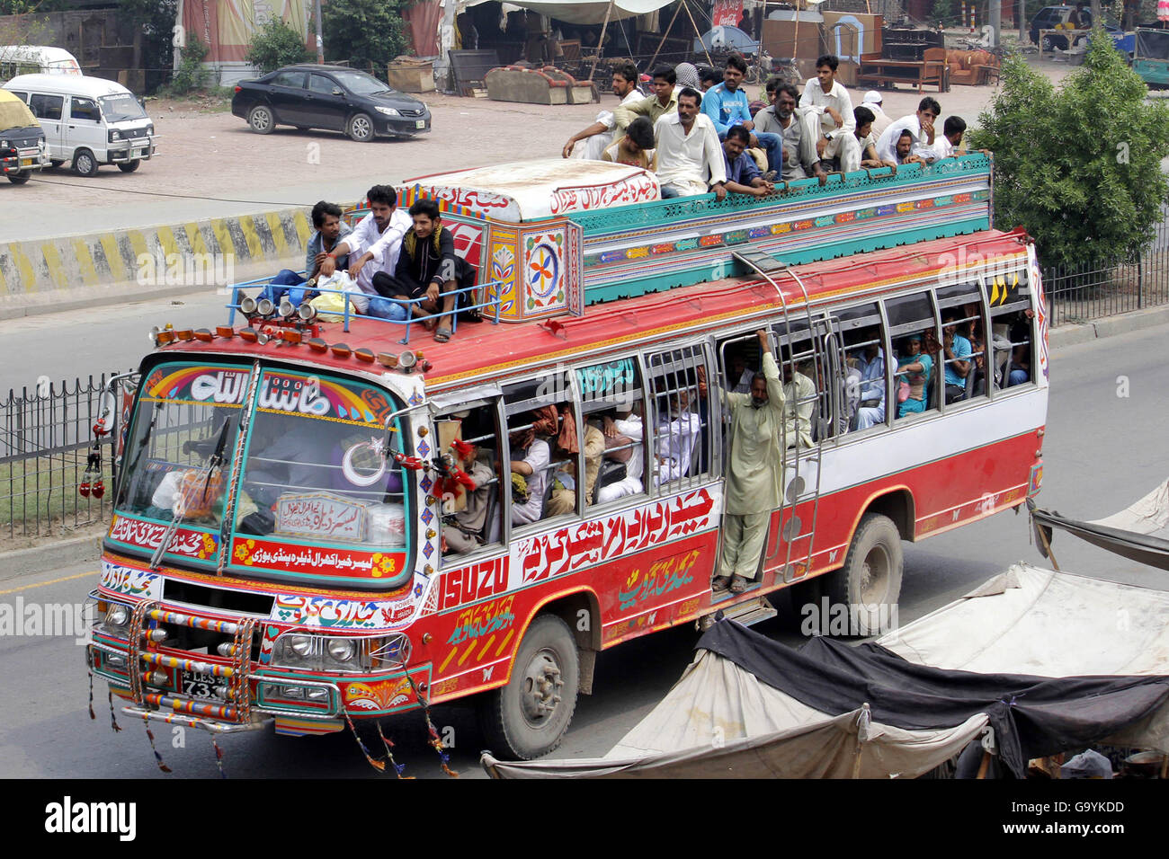 Lahore, Pakistan. 4th July, 2016. Passengers travel on the top of a bus ...