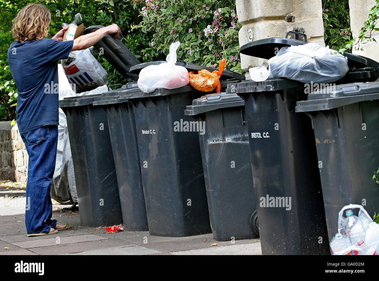Tories warn of microchip 'spies' on household bins. A man empties waste ...