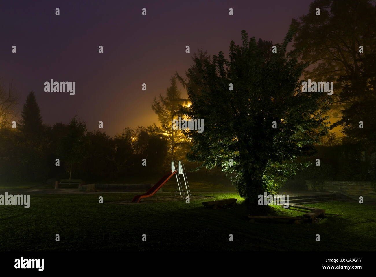 an empty playground with a red slide at night with fog and creepy atmosphere Stock Photo - Alamy