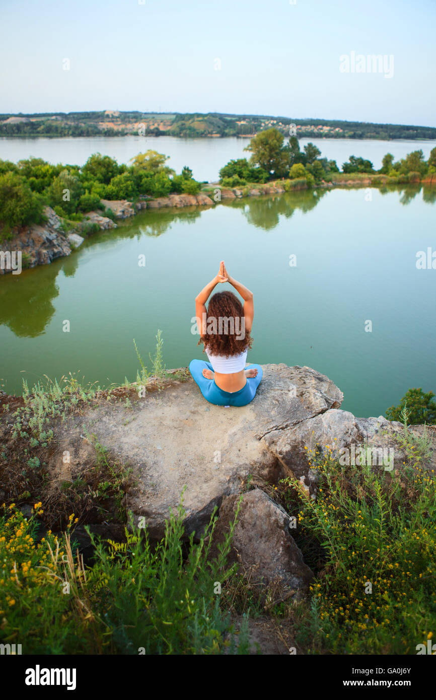 Young woman is practicing yoga near river Stock Photo - Alamy
