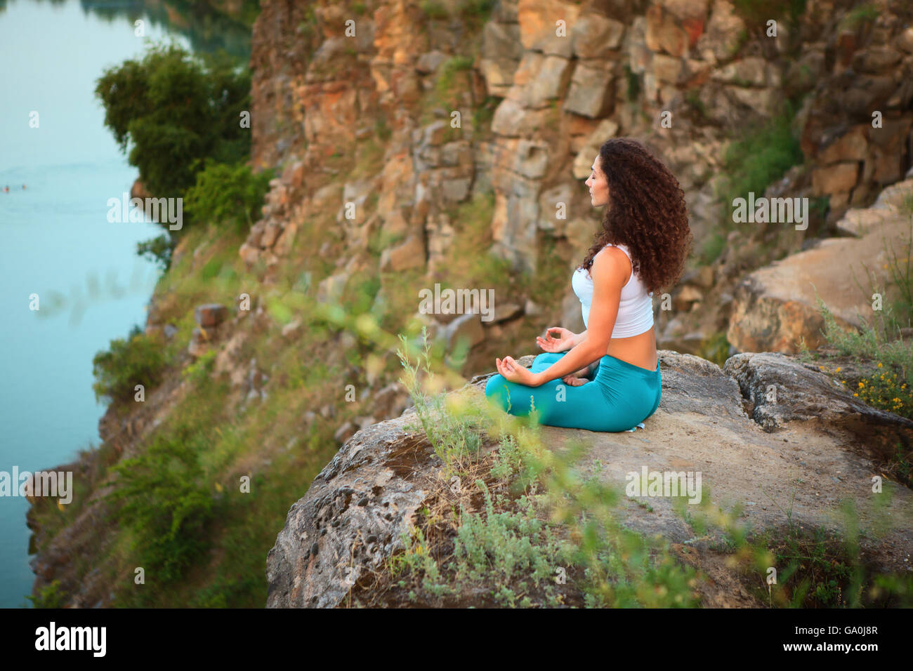 Young woman is practicing yoga near river Stock Photo - Alamy