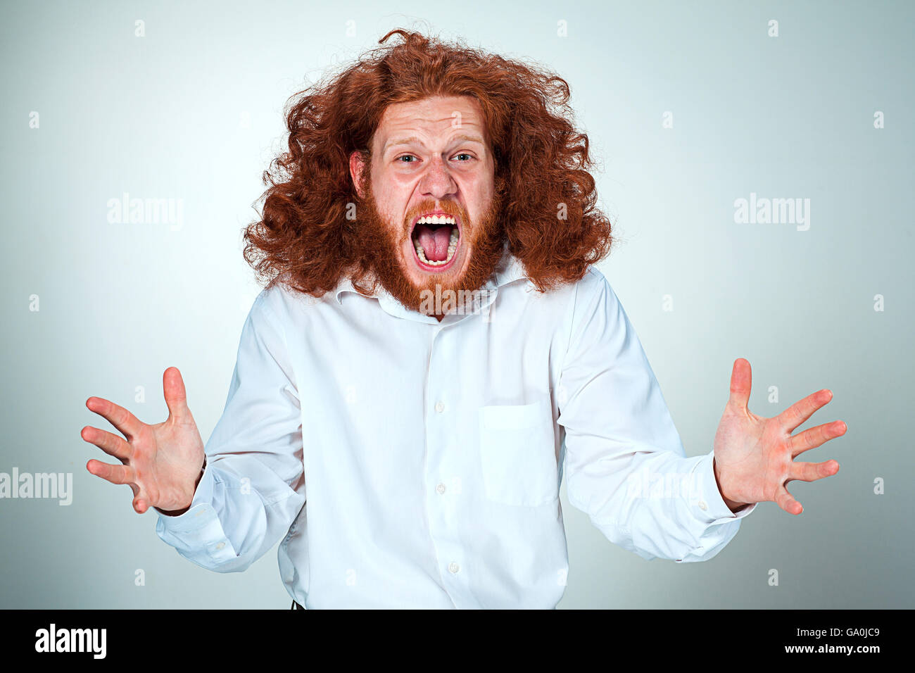 Portrait of screaming young man with long red hair and shocked facial ...