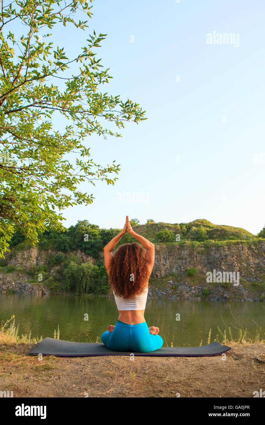 Young woman is practicing yoga near river Stock Photo - Alamy