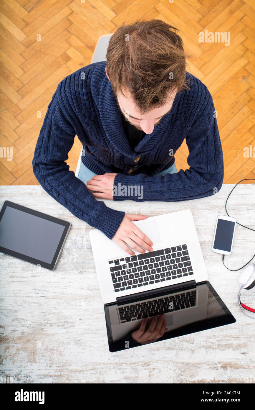 A young man working online from home with his laptop computer and ...