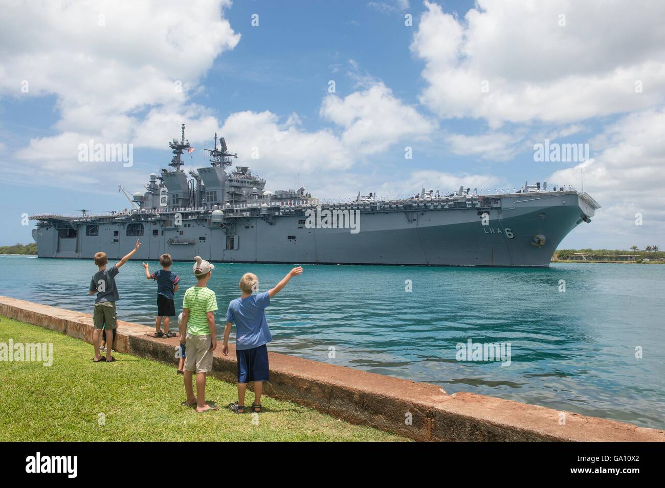Children wave to the U.S Navy America-class amphibious assault ship USS ...