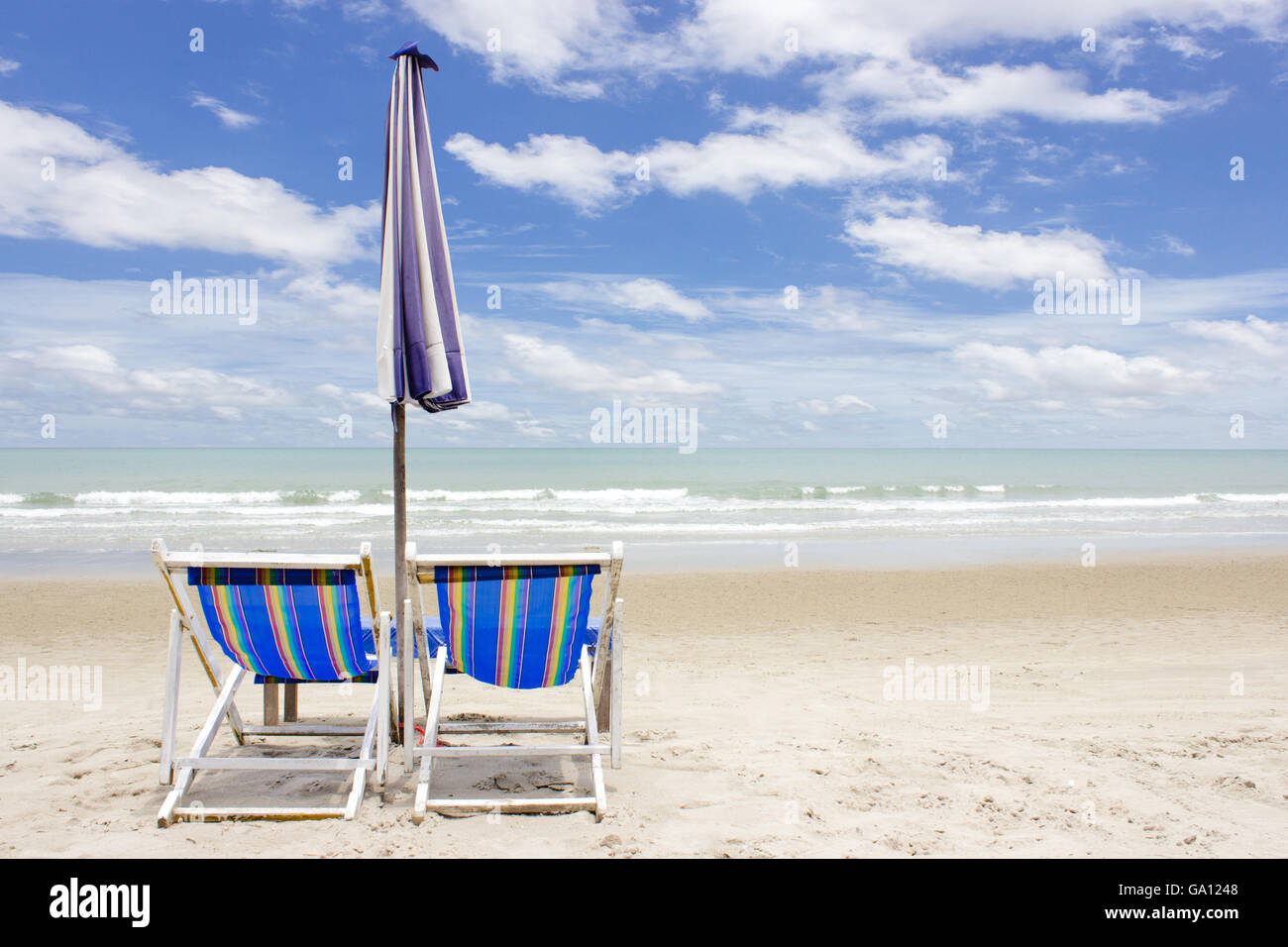 Two beach lounge chairs and tent on beach and blue sky background in ...