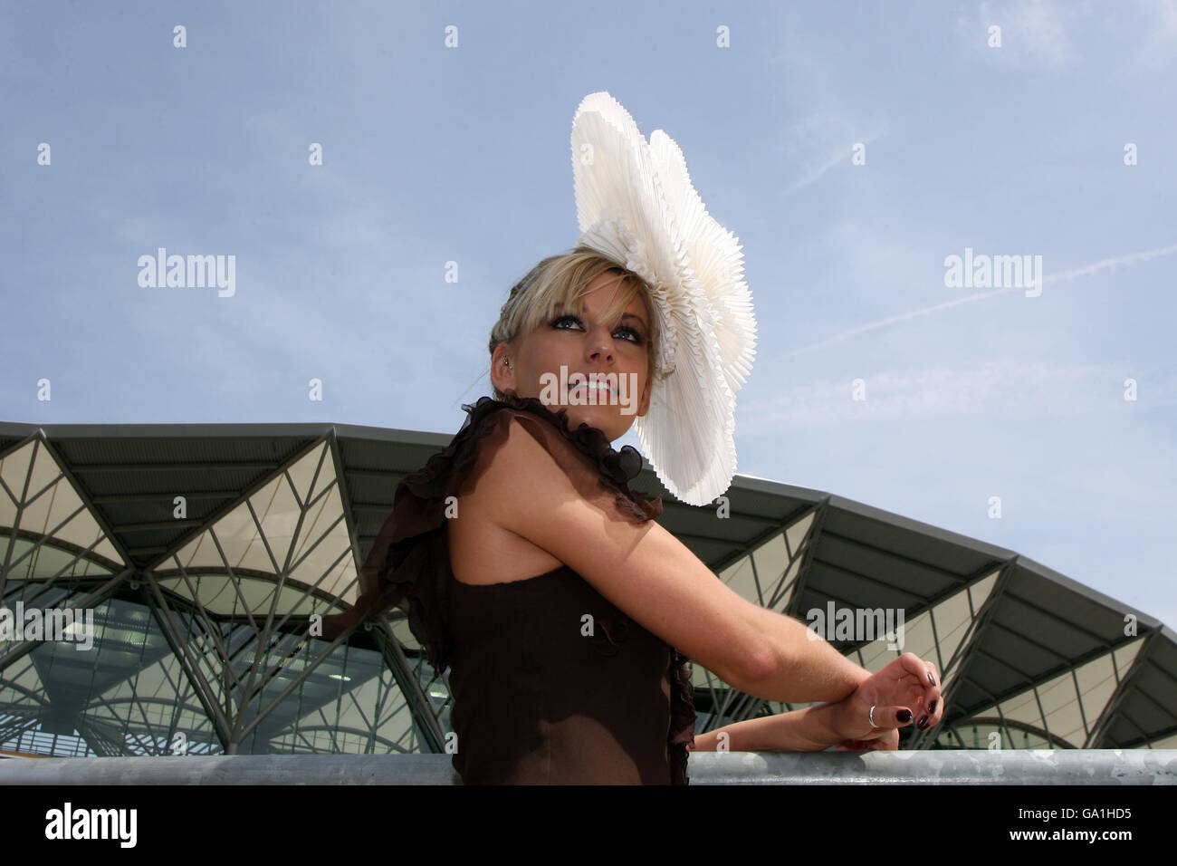 A racegoer poses for photographers in front of the main grandstand at ...