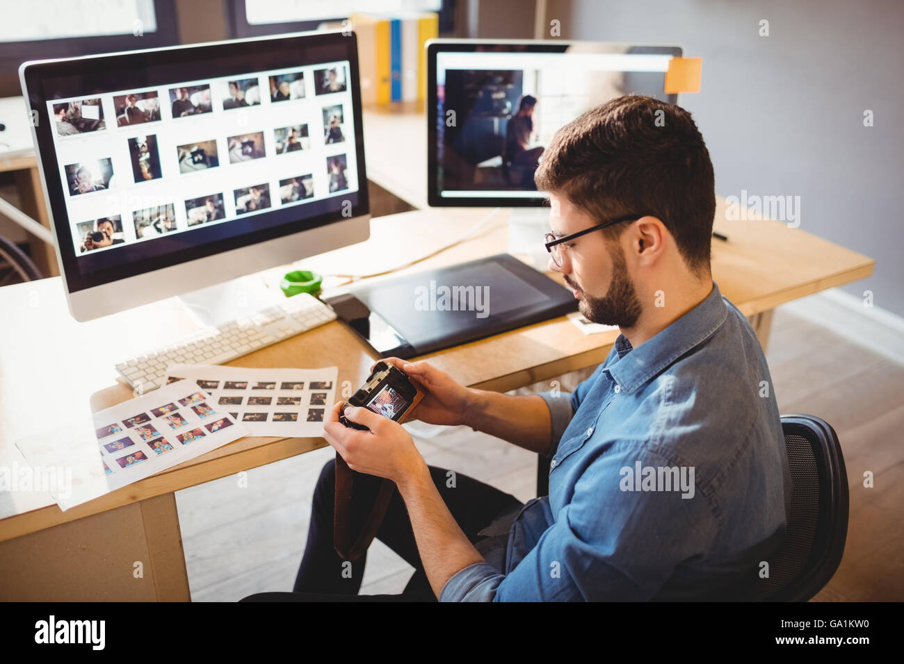 Graphic designer looking at pictures in digital camera Stock Photo - Alamy