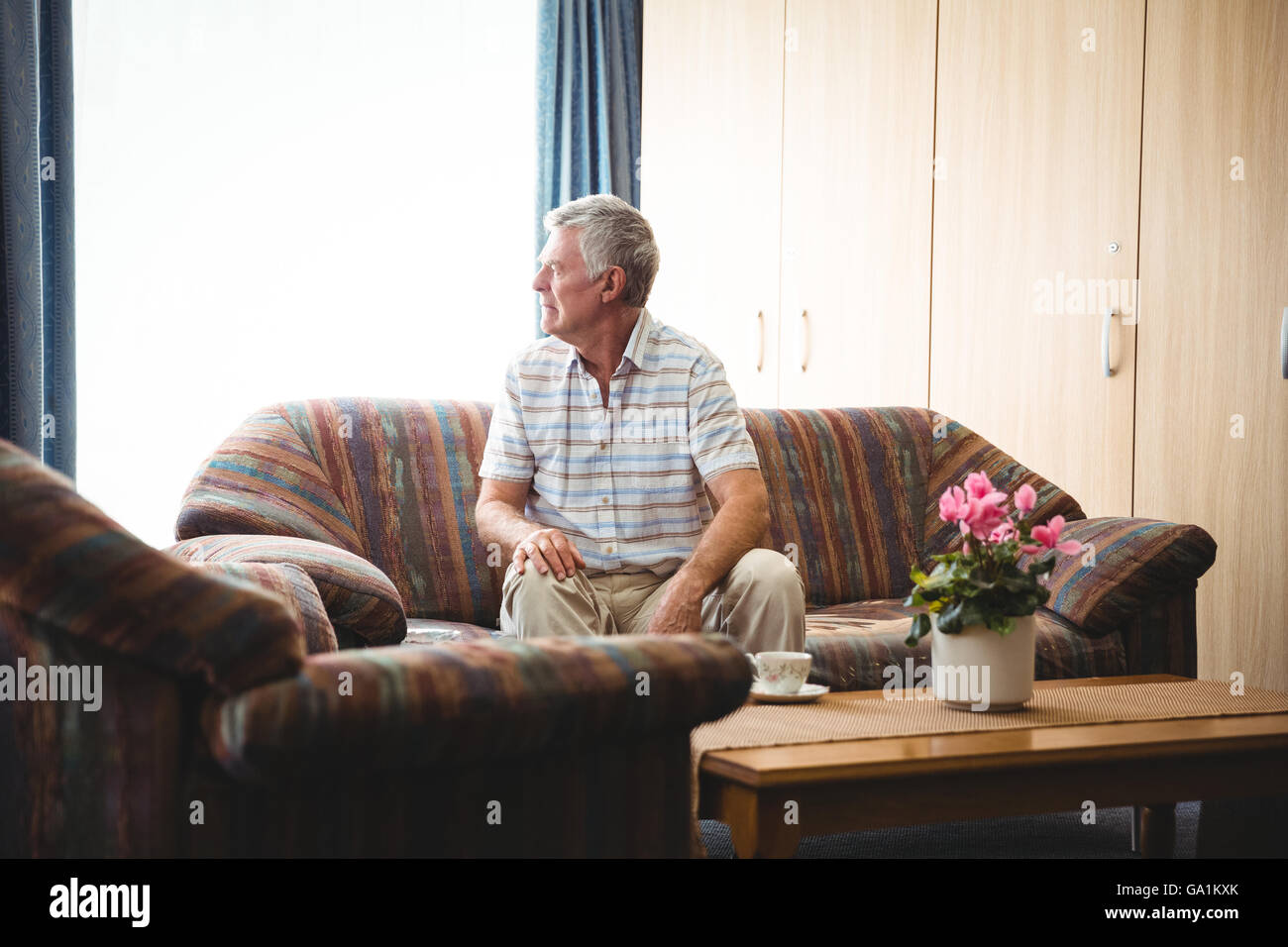 Senior man sitting on a couch Stock Photo - Alamy