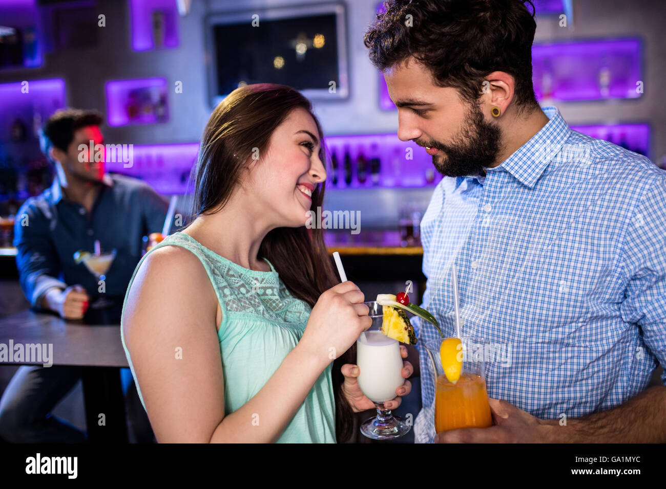 Smiling friends interacting with each other at bar counter while having ...