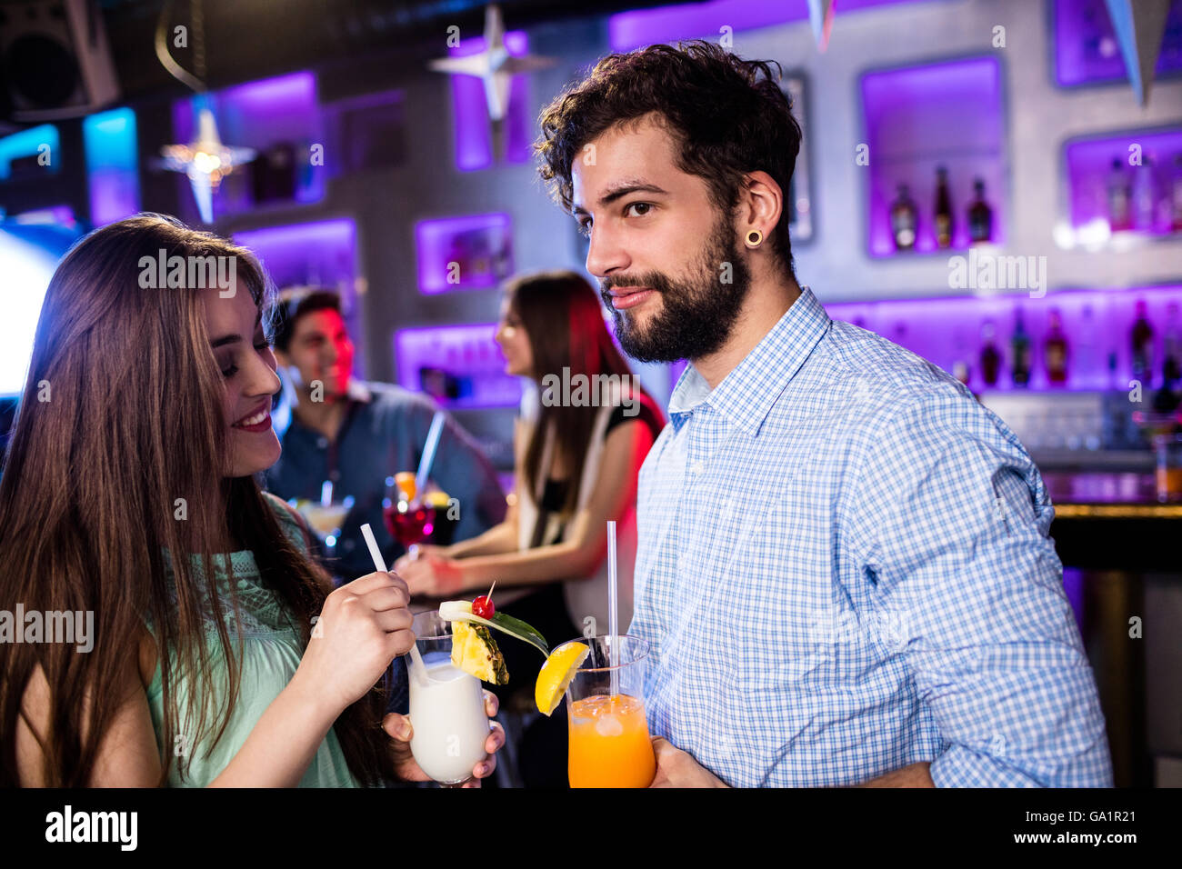 Smiling friends having cocktail at bar counter Stock Photo - Alamy