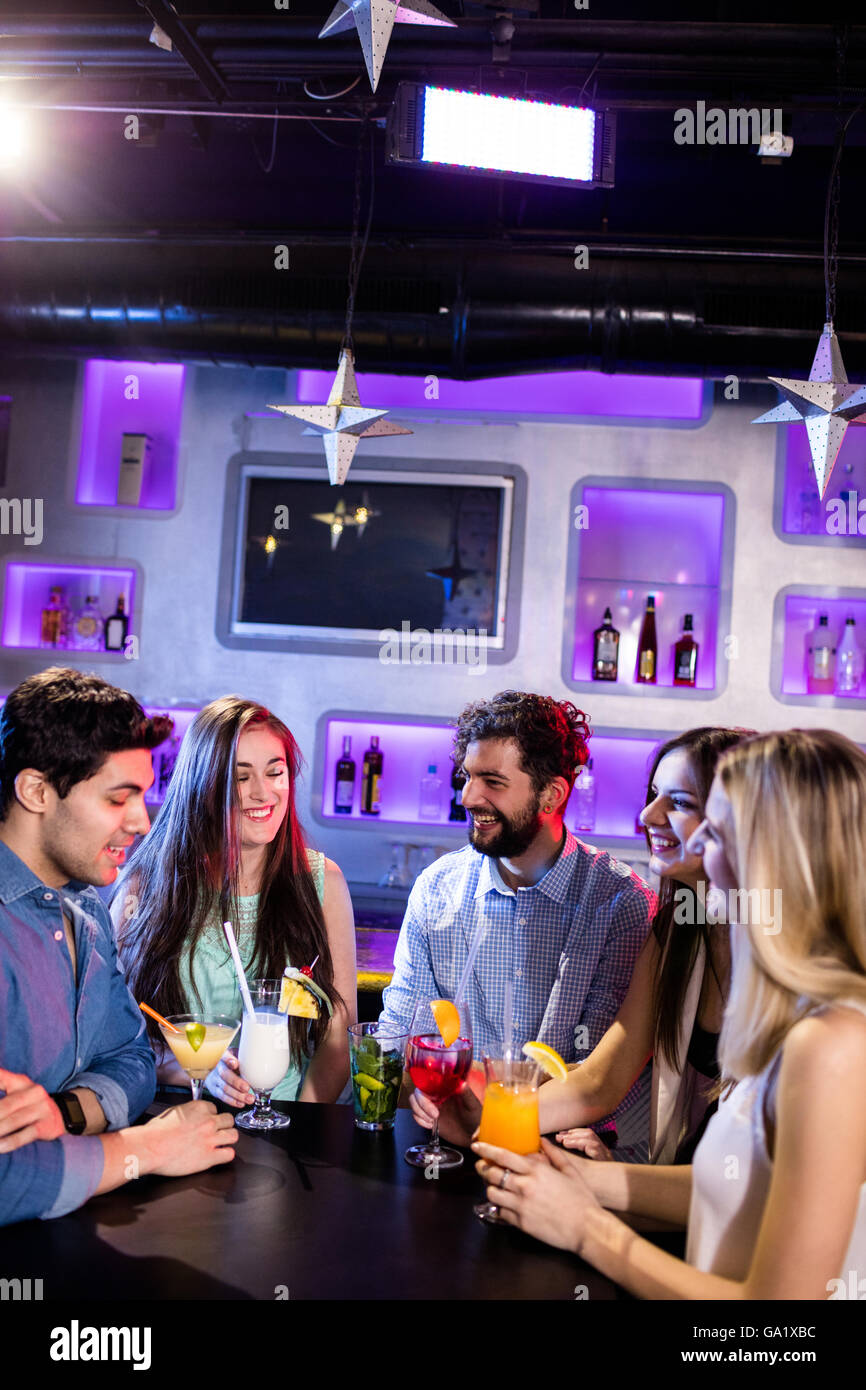 Group of friends interacting with each other at bar counter while ...