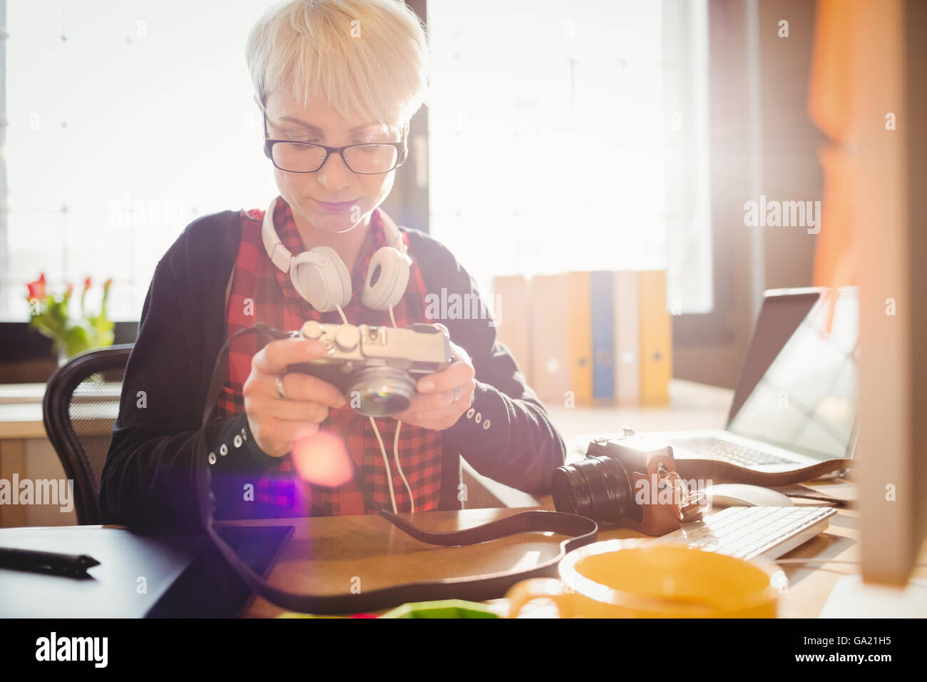Graphic designer looking at pictures in digital camera Stock Photo - Alamy
