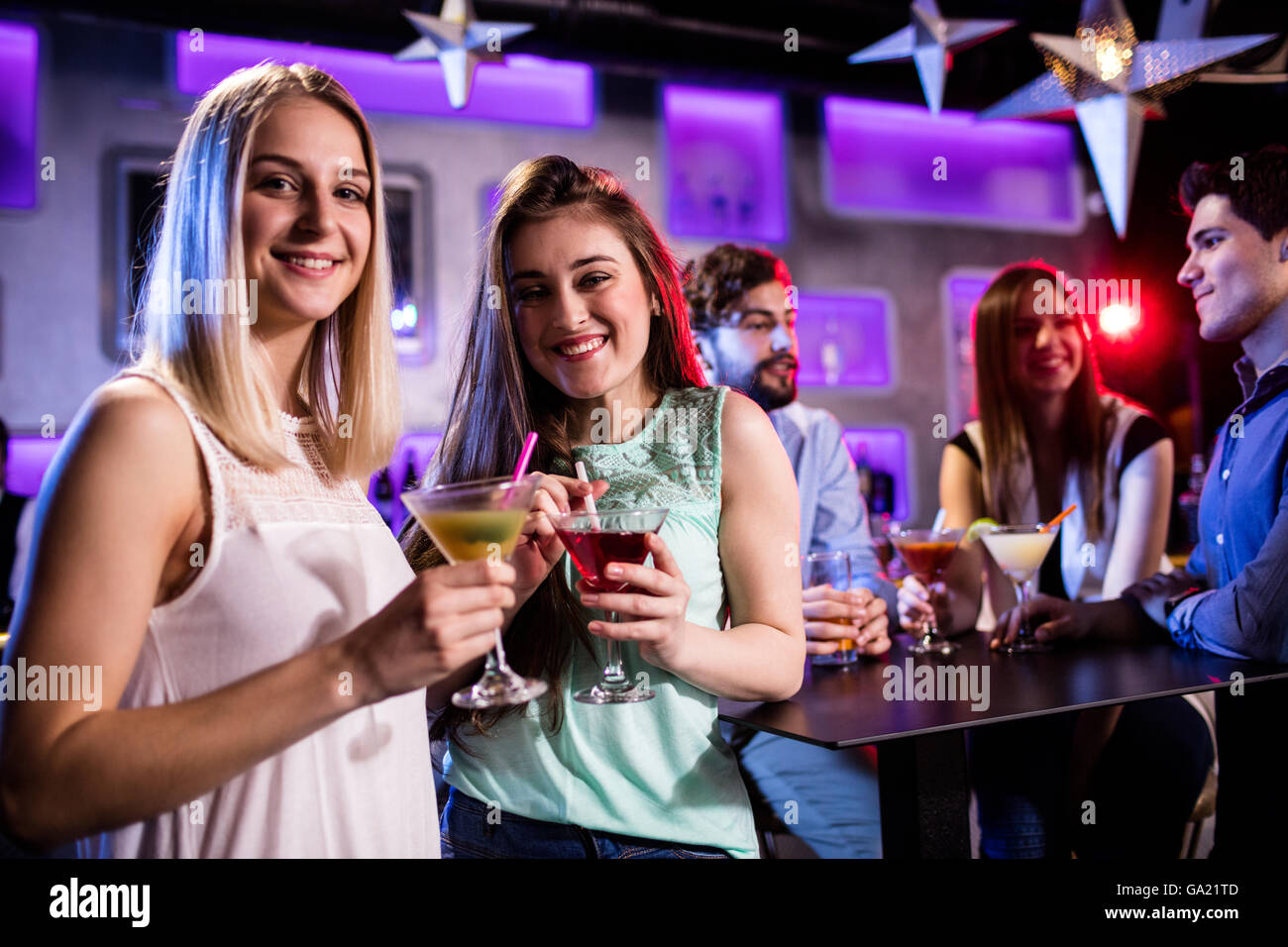 Smiling friends having cocktail at bar counter Stock Photo - Alamy