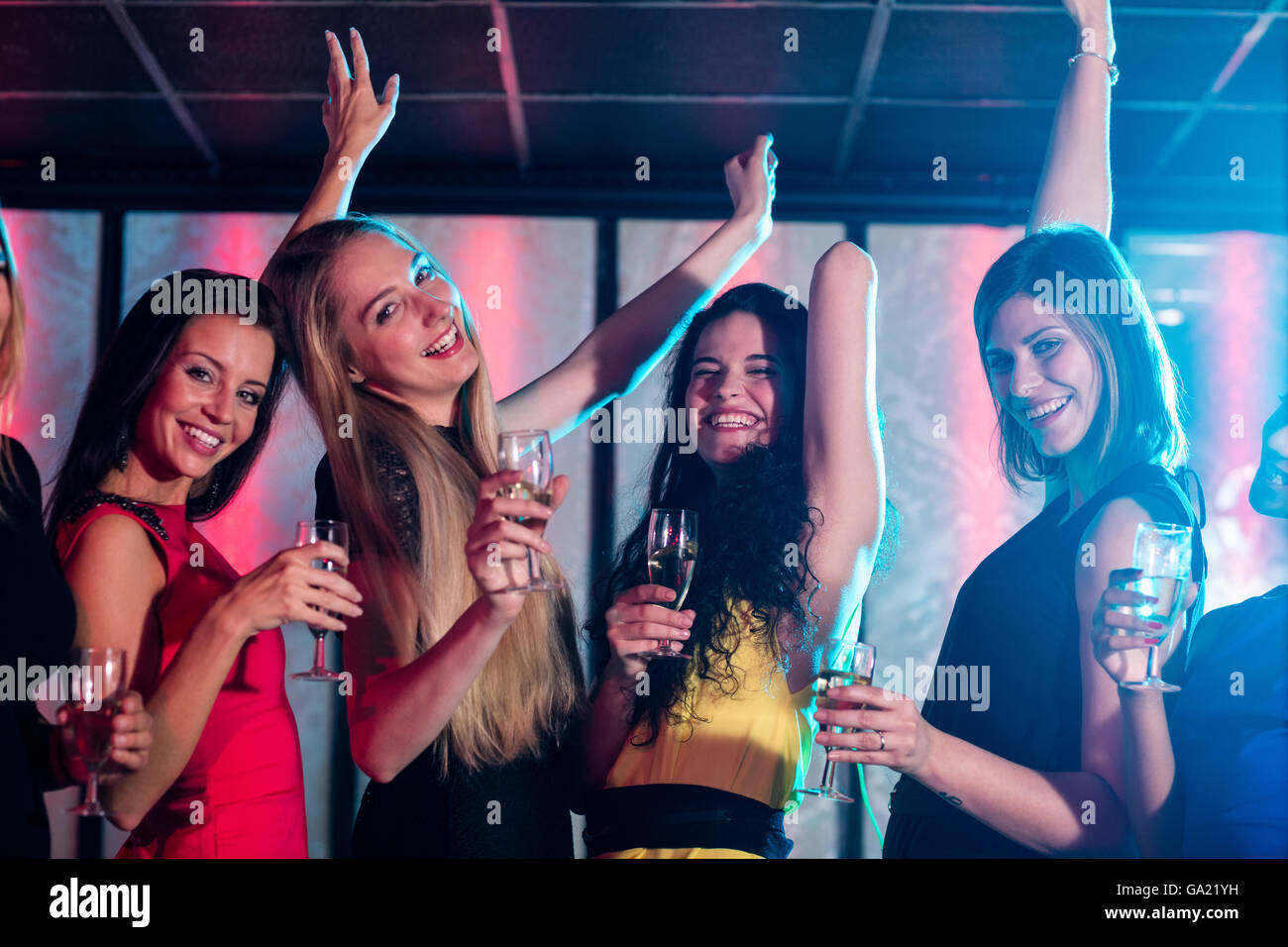 Smiling friends holding glass of champagne while dancing Stock Photo ...