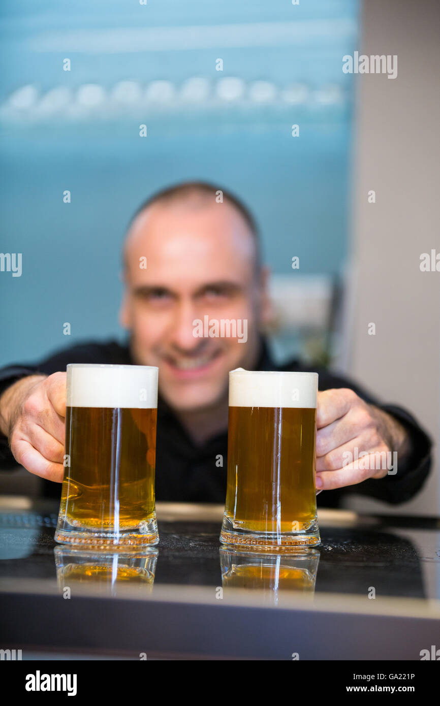 Bar tender offering beer Stock Photo - Alamy
