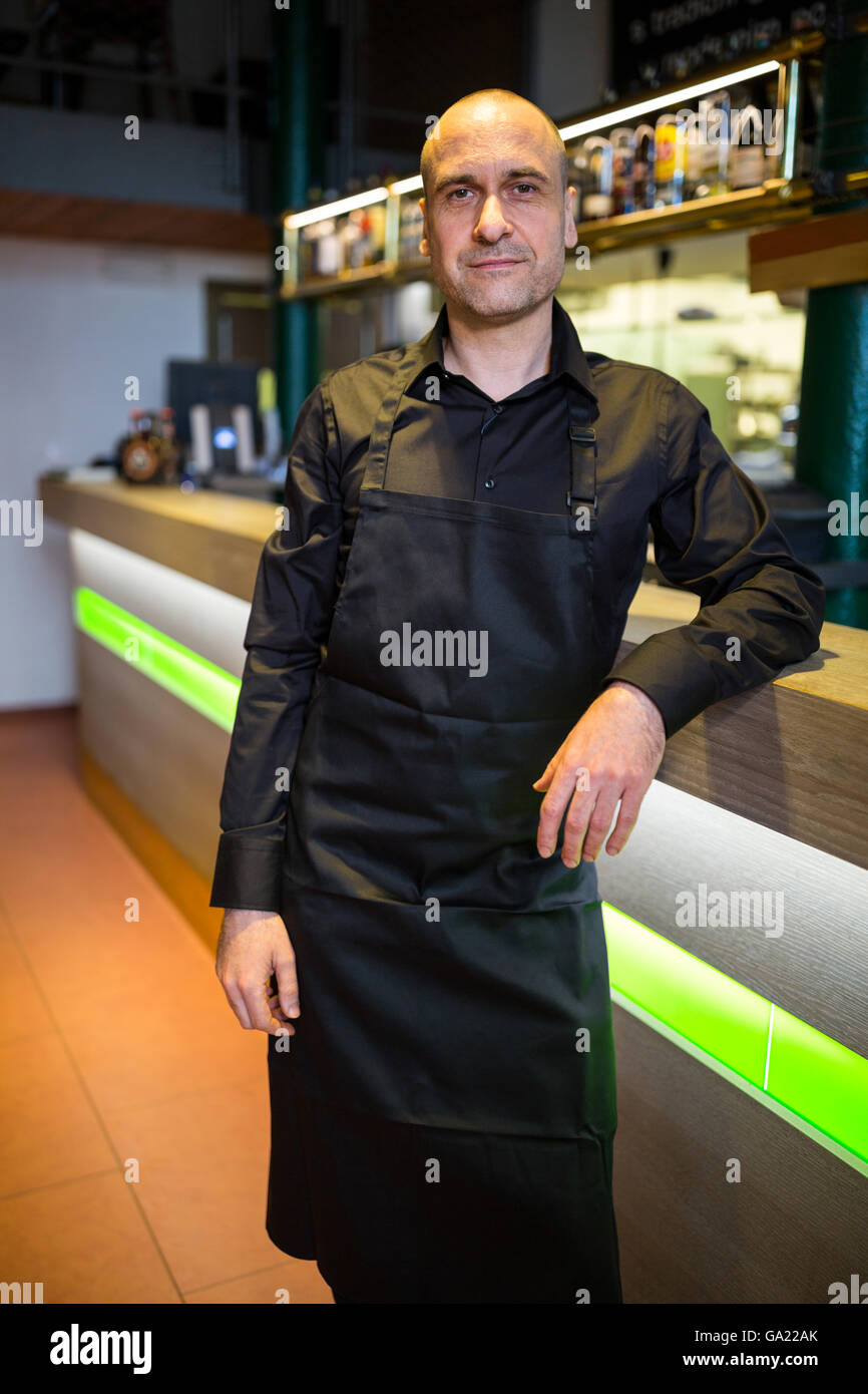 Bar tender leaning at bar counter Stock Photo - Alamy