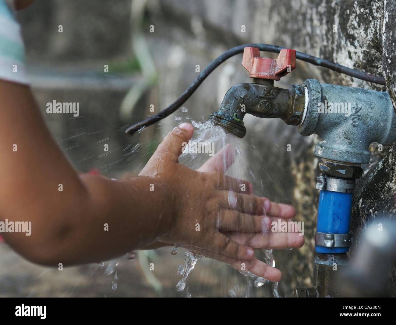 Child enjoying playing with the refreshing cold water in the heat of ...