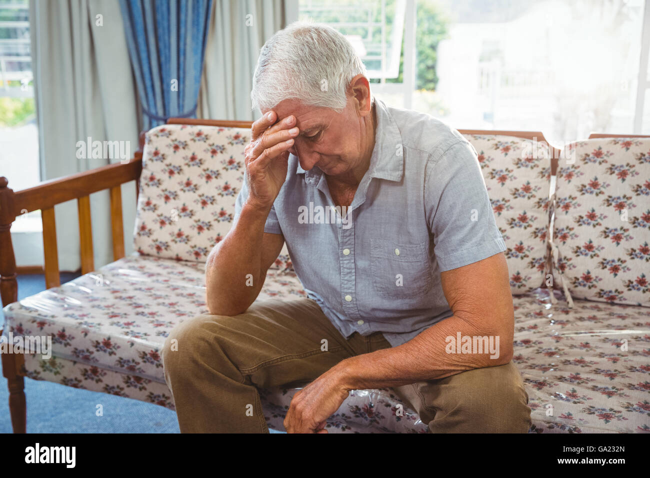 Sad senior man sitting on a couch Stock Photo - Alamy