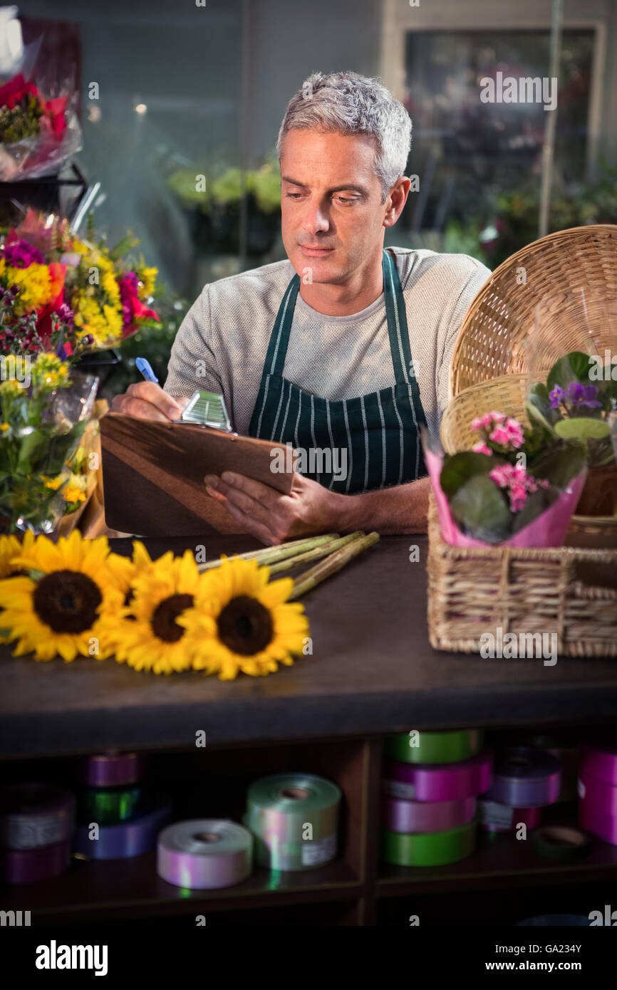 Male florist writing on clipboard Stock Photo - Alamy