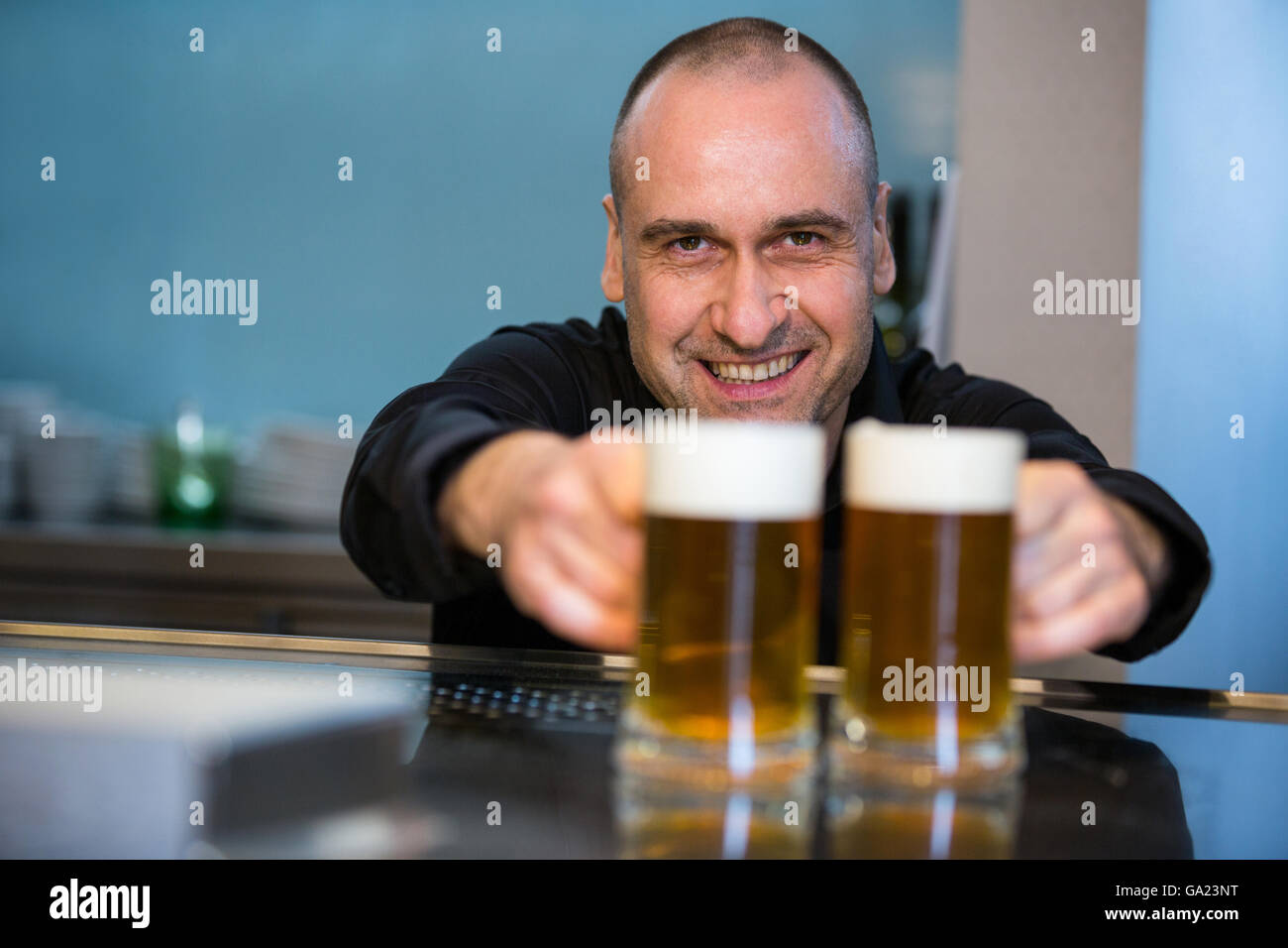 Portrait of bar tender offering beer Stock Photo - Alamy